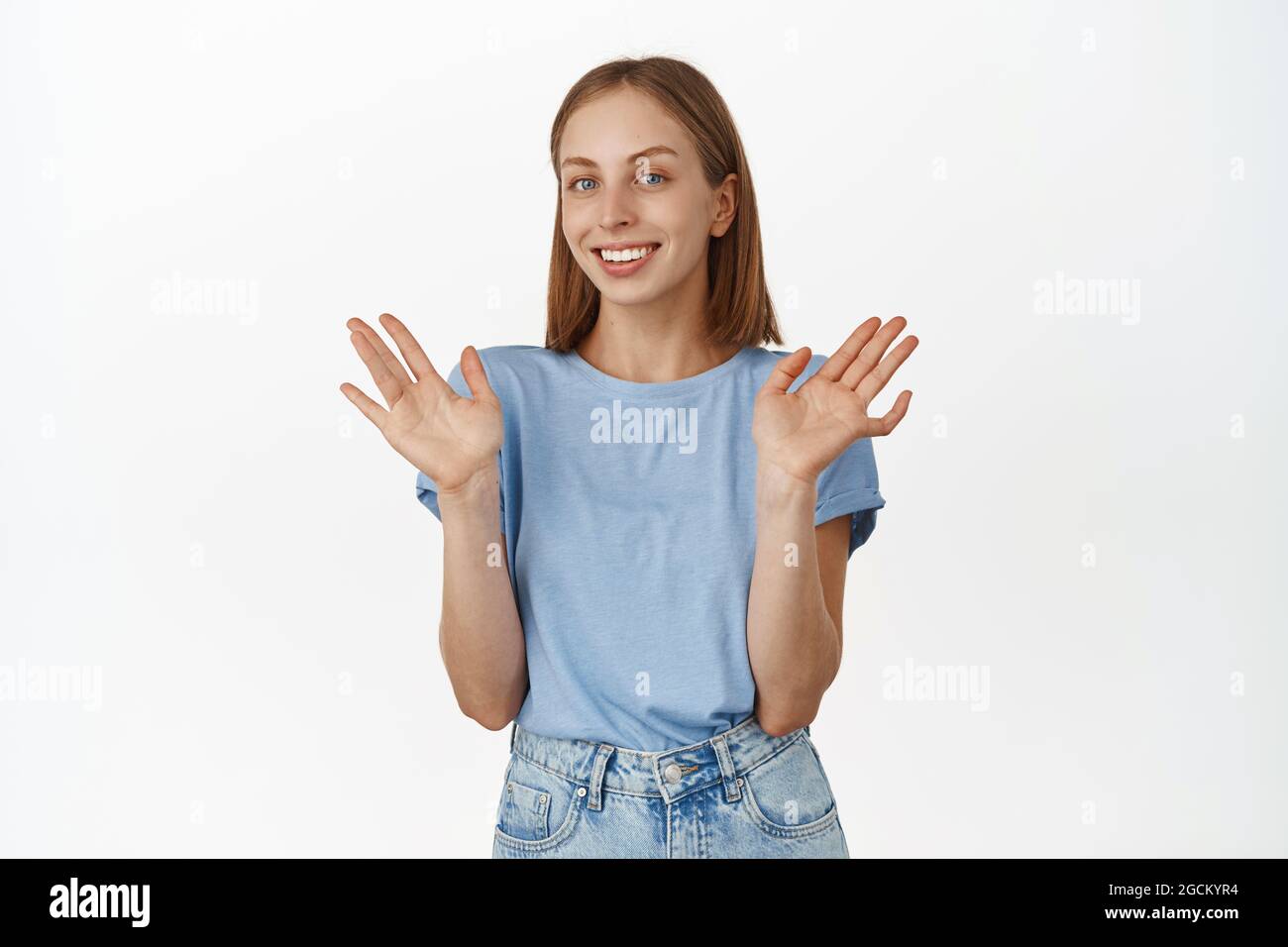 She is not involved. Smiling blond girl raising empty hands up and ...