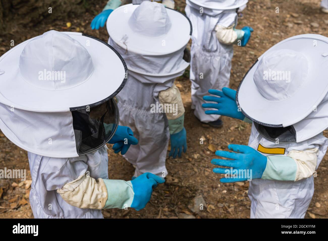 Anonymous group of children in white protective costumes and gloves ...