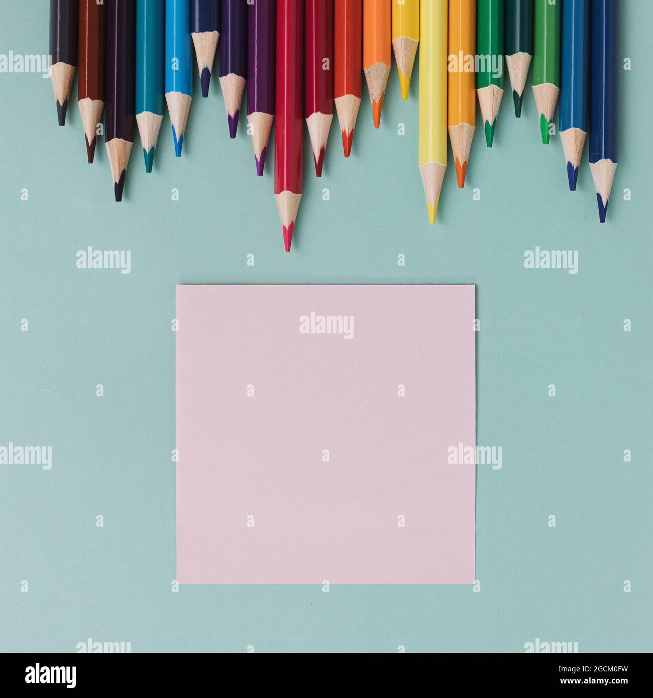 Colored pencils and a sheet for notes lie on a blue background. Top ...