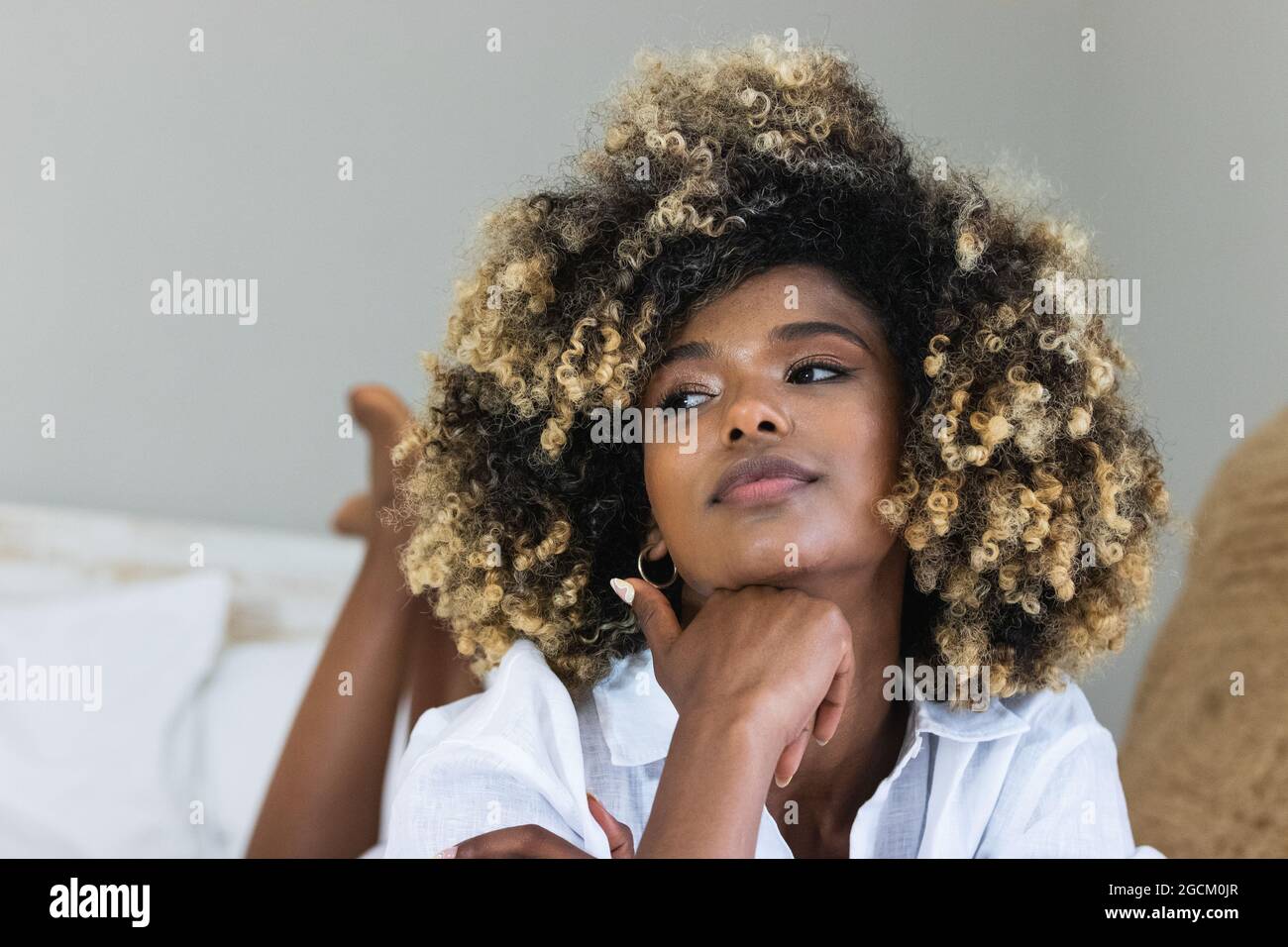 Attractive African American female lying down resting on bed and ...