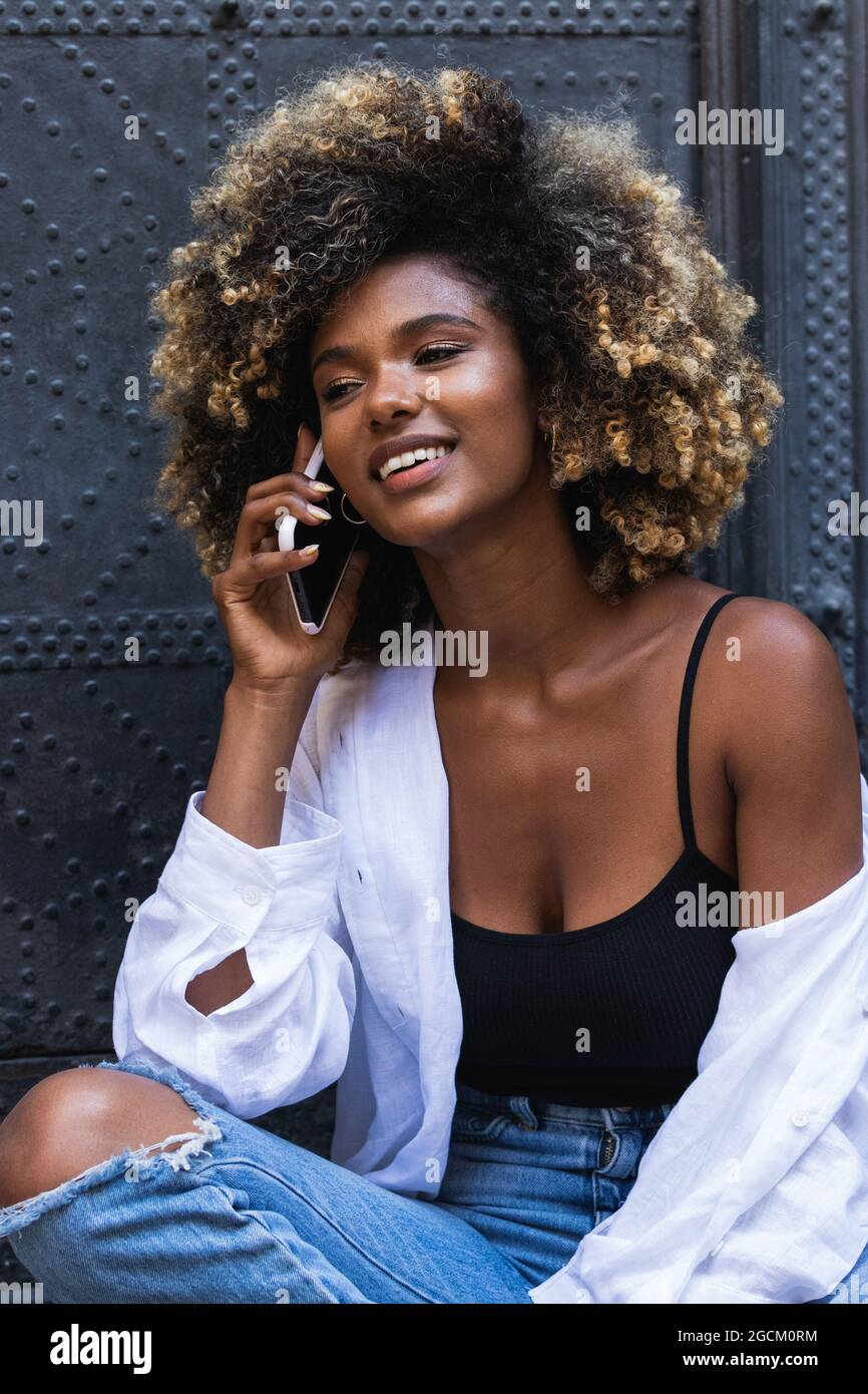 Positive African American female in casual outfit sitting with crossed ...