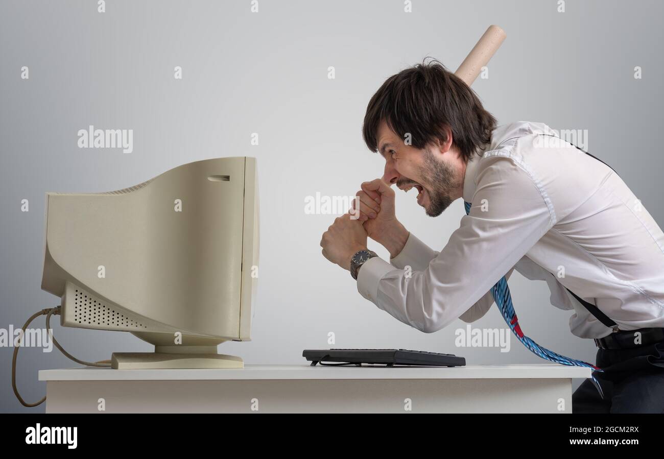 Angry man is destroying old computer with baseball bat in office Stock ...