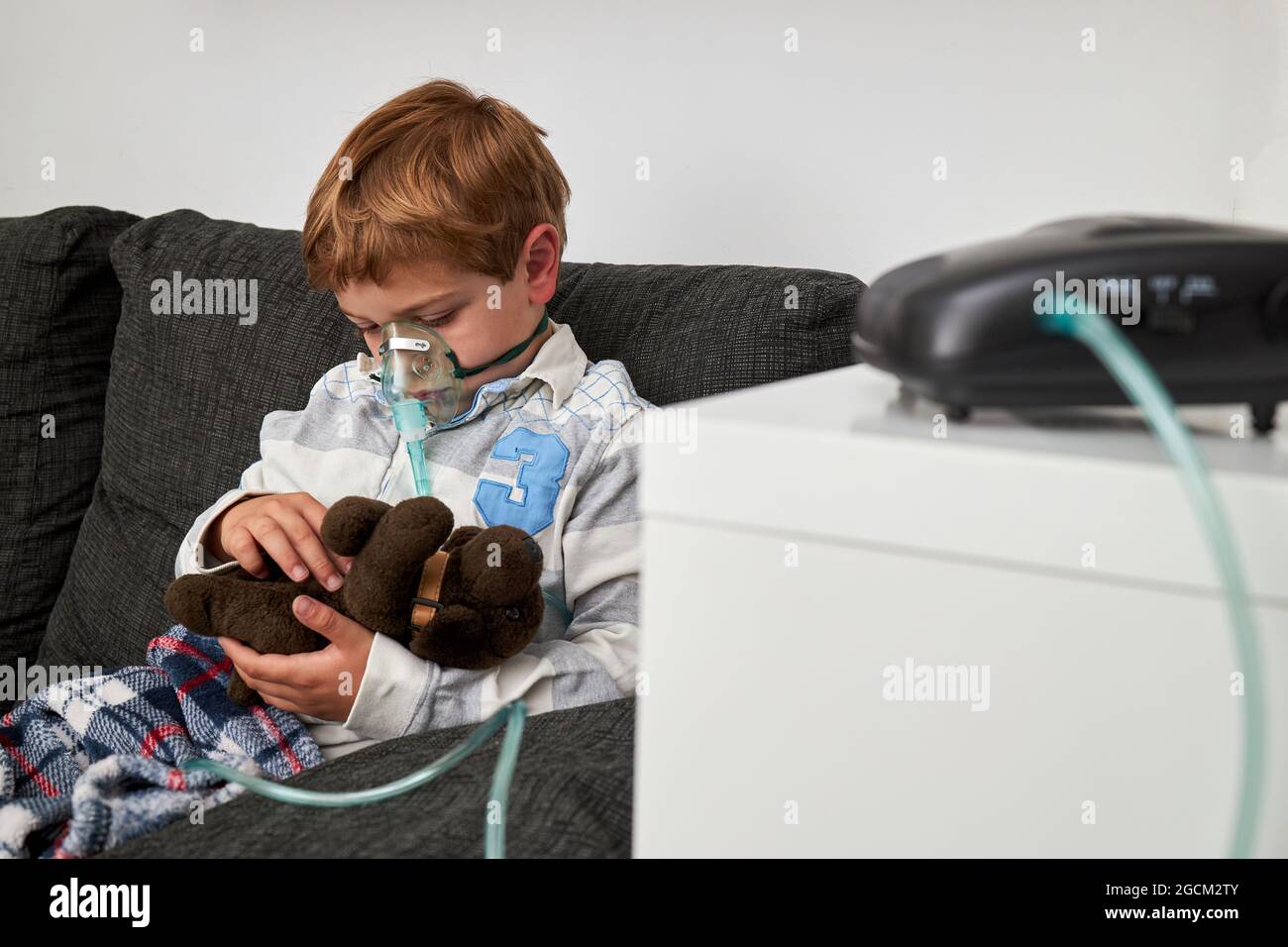 Cheerful child breathing in oxygen mask during inhalation and playing ...