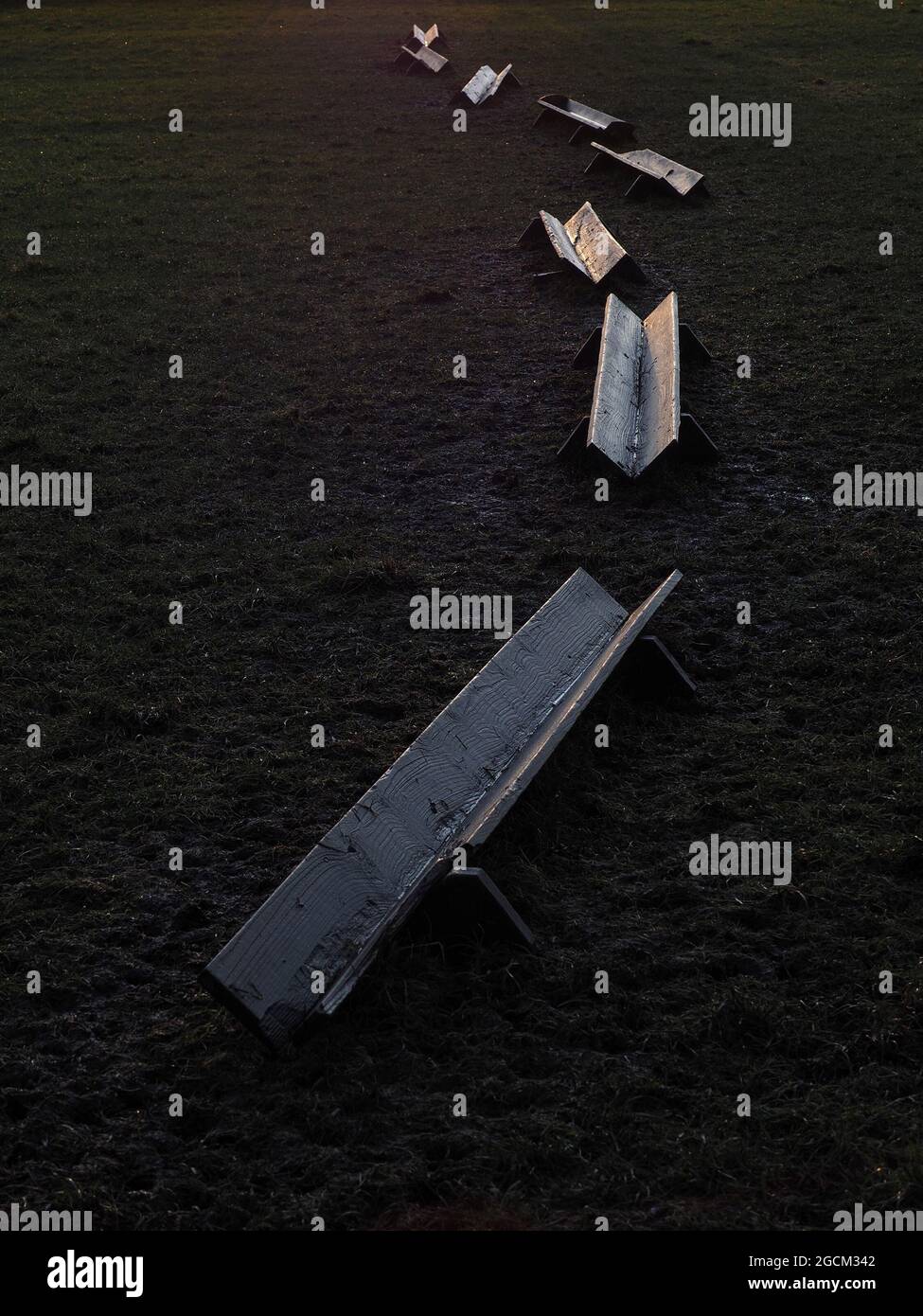 silver grain of backlit wooden V-shape feeding troughs in dramatic ...