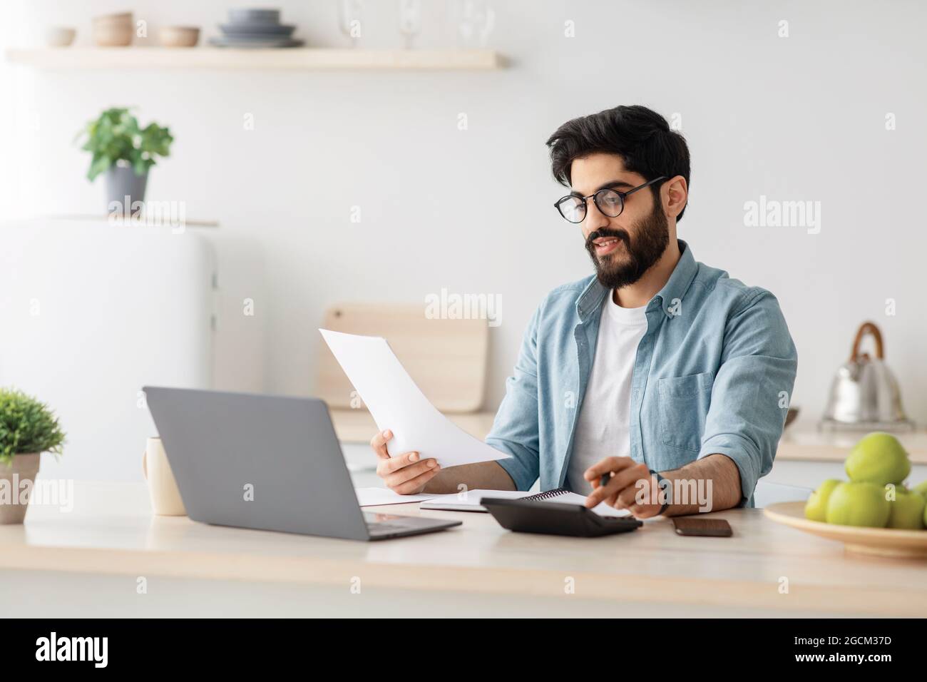 Home accounting, taxes. Happy young arab man in white minimalist ...