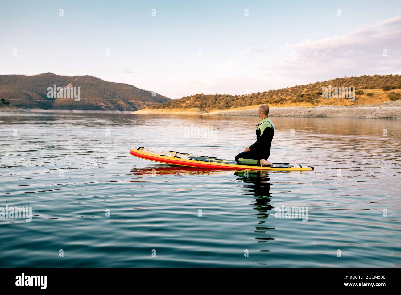 Side view of tranquil male surfer sitting in Thunderbolt pose on ...
