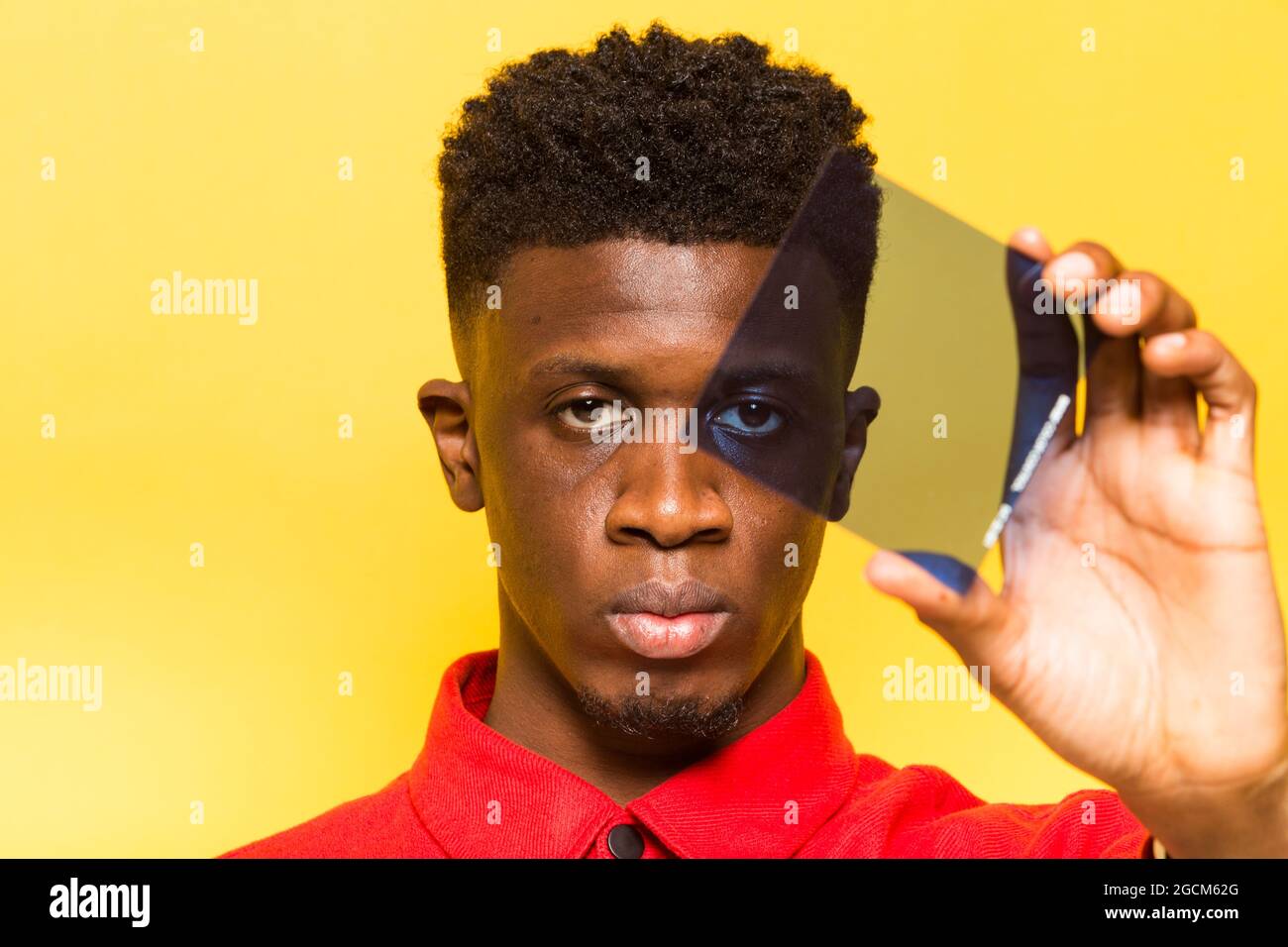 Serious African American male looking at camera through blue color ...