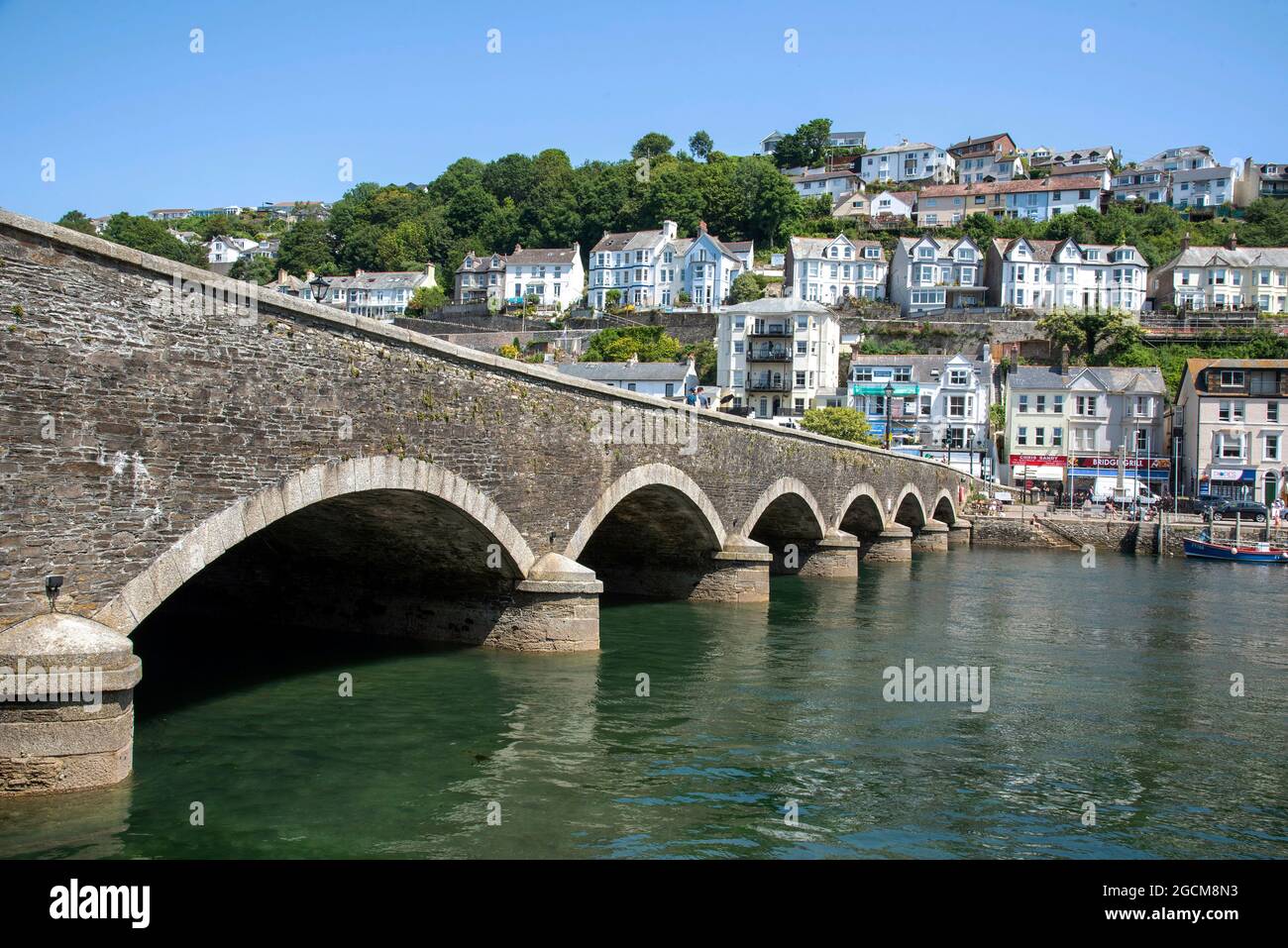 Looe, Cornwall, England, UK. 2021. Stone road bridge crossing the tidal River Looe which devides ...