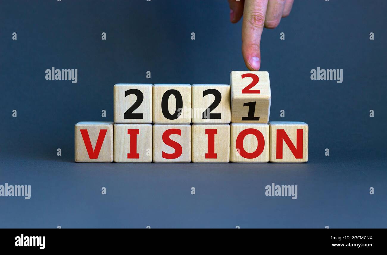 2022 vision new year symbol. Businessman turns a wooden cube and ...