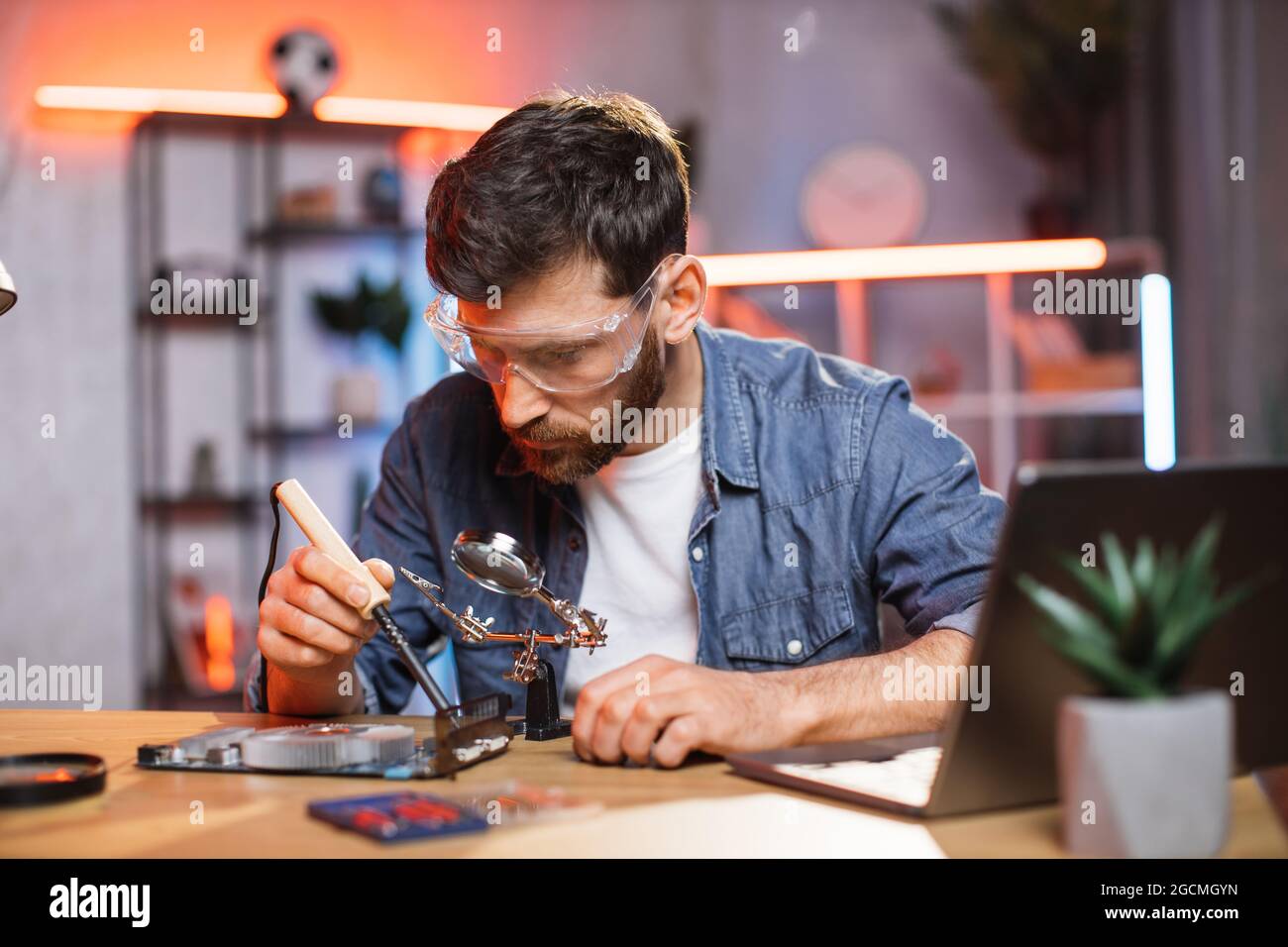 Young man with beard fixing display card from laptop using soldering ...