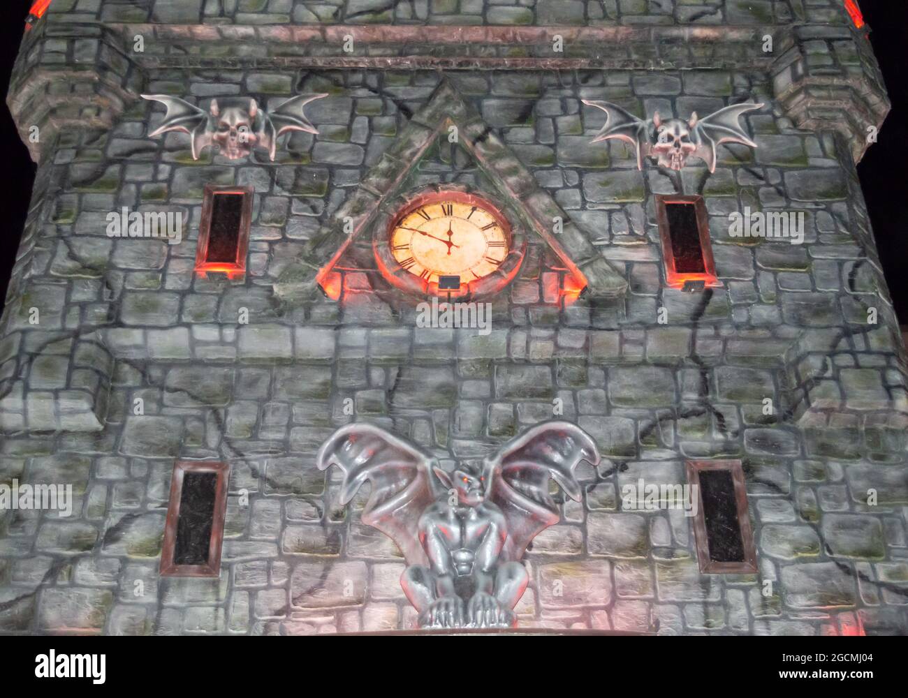 Halloween stone castle with luminous clock and gargoyles. Close-up ...