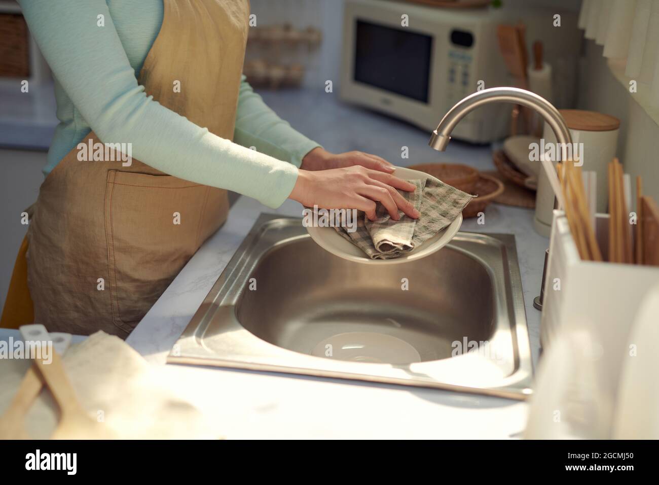 Kitchen porter cleaning white plates in sink in professional kitchen ...