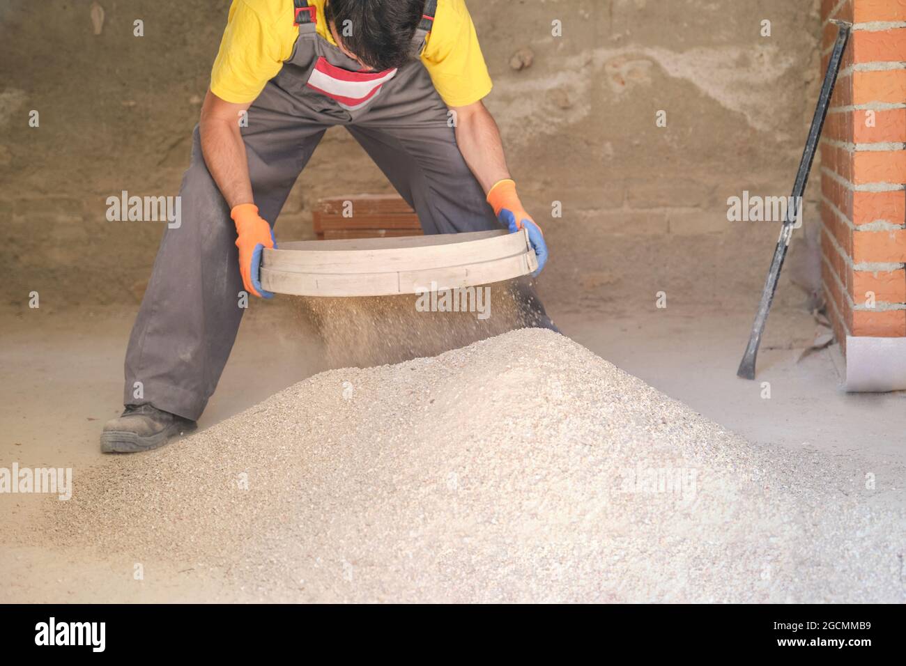 Young builder sieving sand at a construction site Stock Photo - Alamy