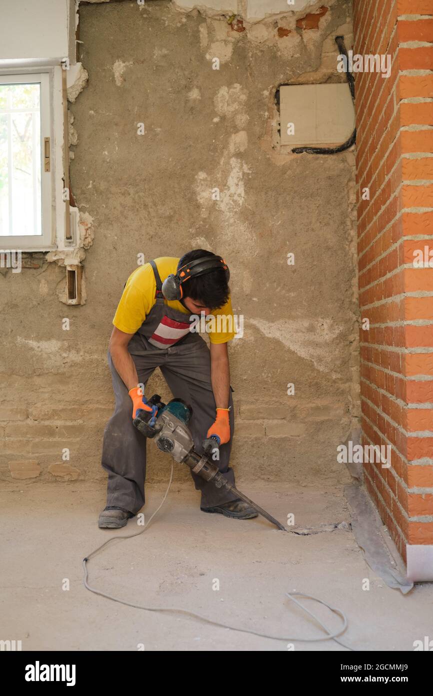 Young builder breaking up a house floor with a jackhammer Stock Photo ...