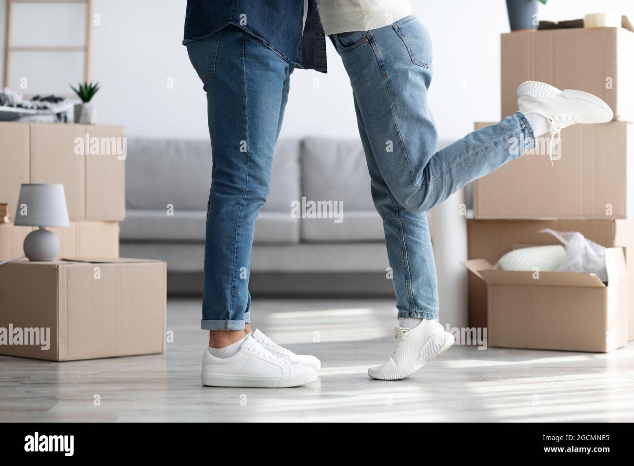 Legs of hugging man and woman standing among moving boxes Stock Photo ...