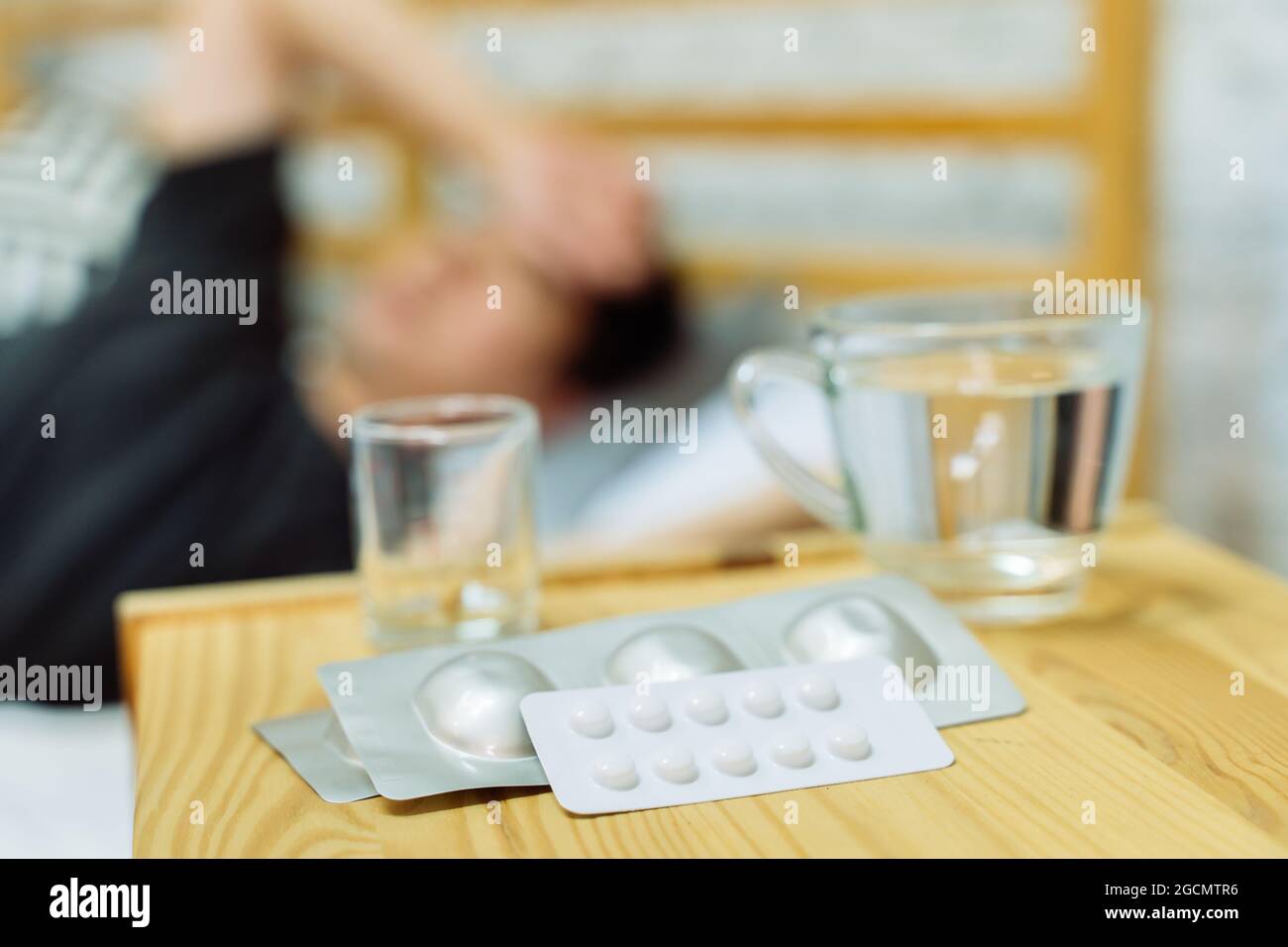 Young Asian man feeling sick and ill lying on bed with medicines ...