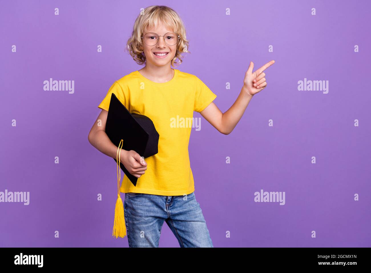 Photo of graduate boy hold bachelor hat show empty space wear yellow t ...