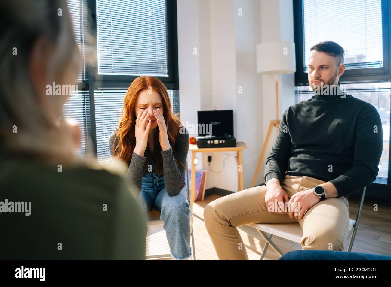 Portrait of sad crying young woman sharing problem sitting in circle ...