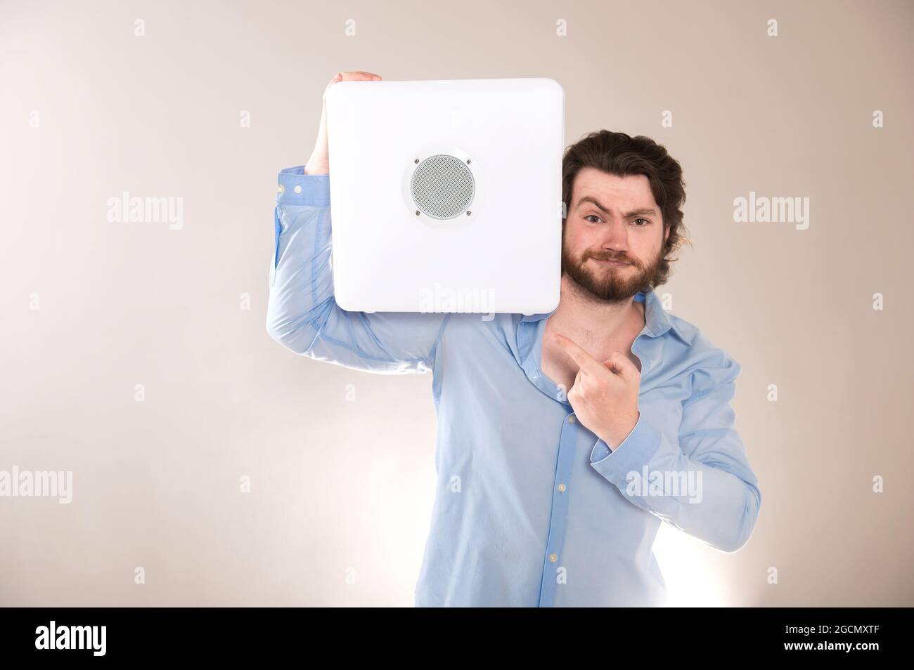 Young attractive man holding white portable bluetooth speaker on ...