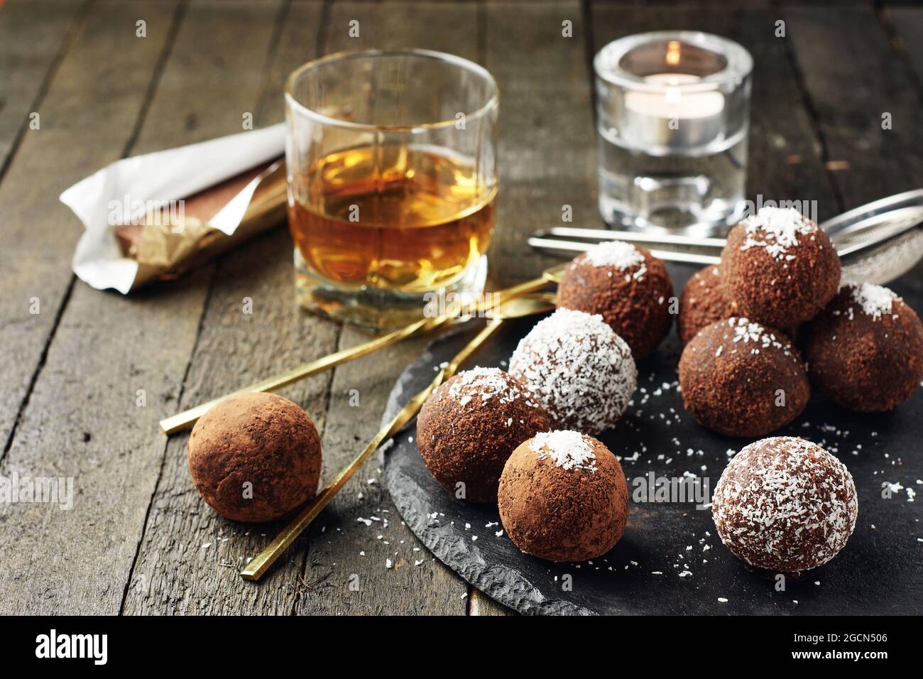 Chocolate rum balls with coconut flakes, sweet candies on a dark ...