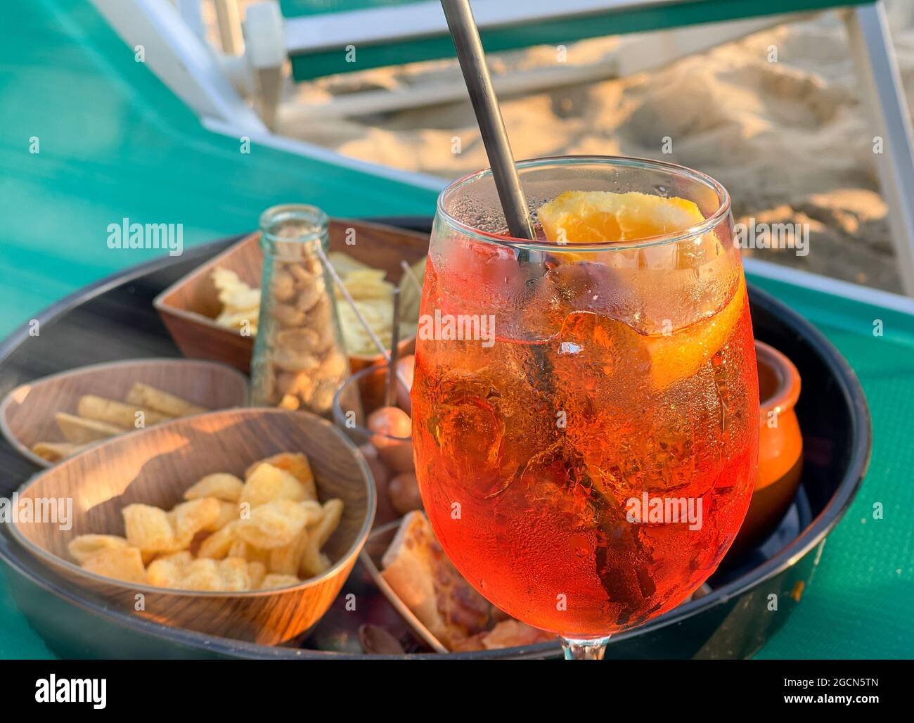 Red glass of aperitif. Appetizers on a green table outdoor. Summer ...
