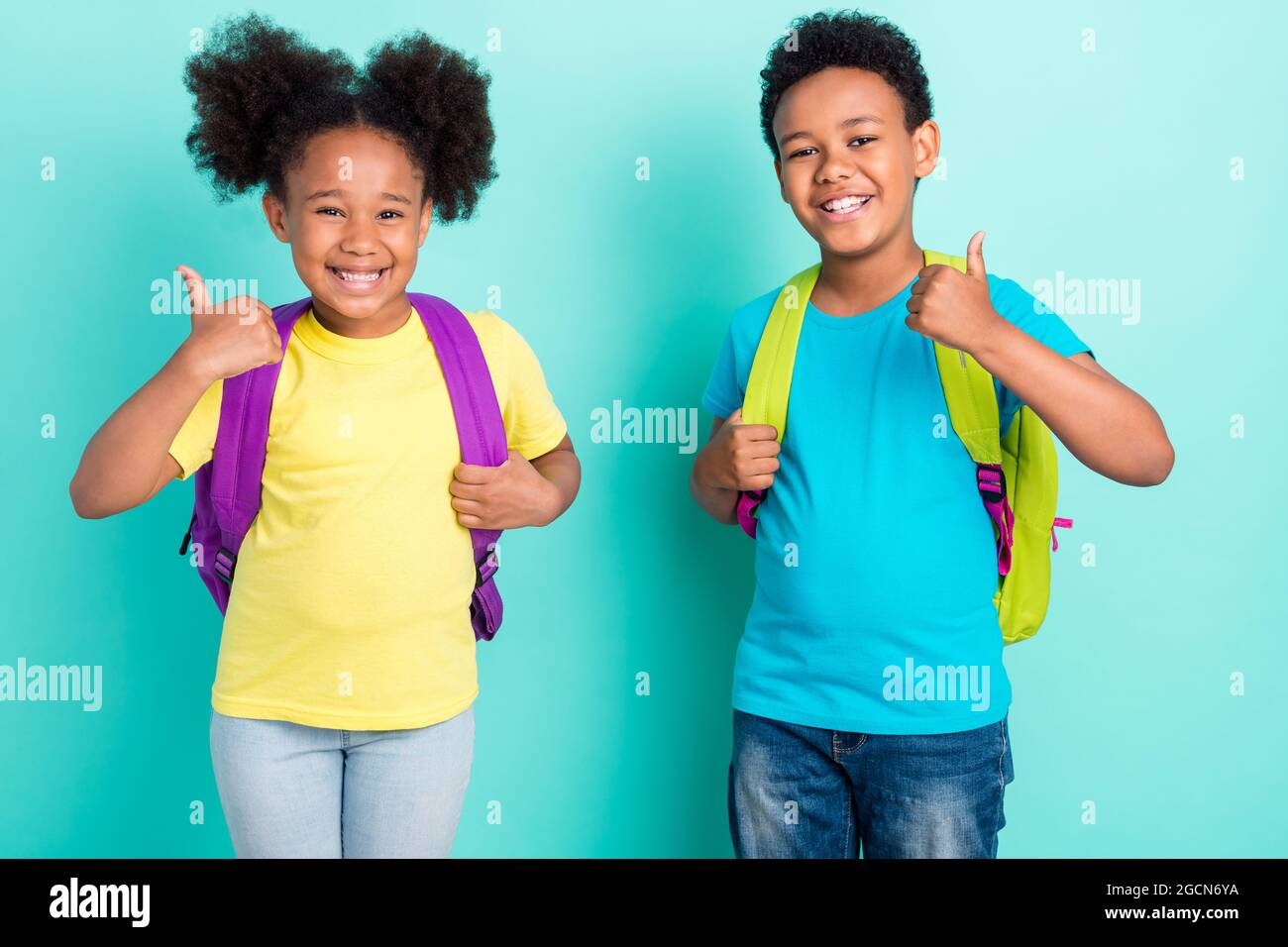 Portrait of two nice cheerful kids going back to primary school showing ...