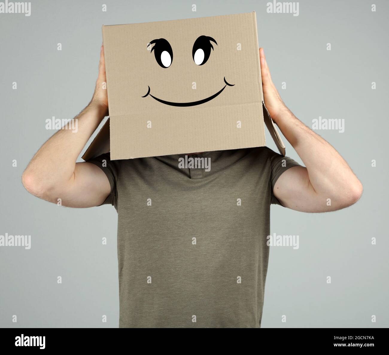 Man with cardboard box on his head on grey background Stock Photo - Alamy