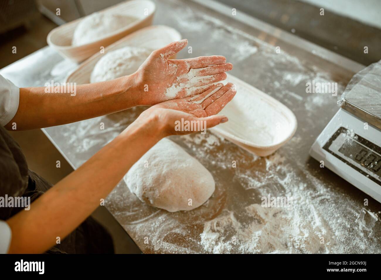 Woman shows palms covered with flour in contemporary craft bakery shop ...