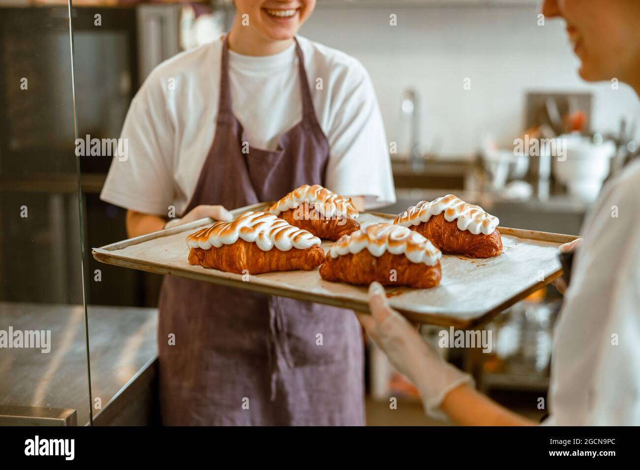 Positive women hold delicious decorated croissants in craft bakery shop ...