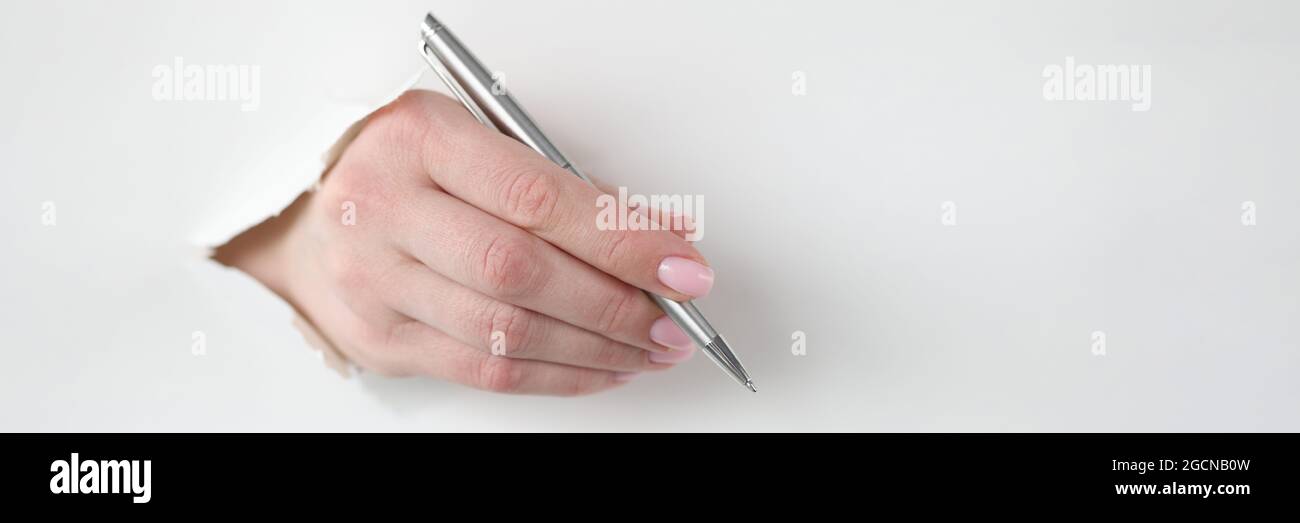 Female hand holds pen through hole in white paper Stock Photo - Alamy