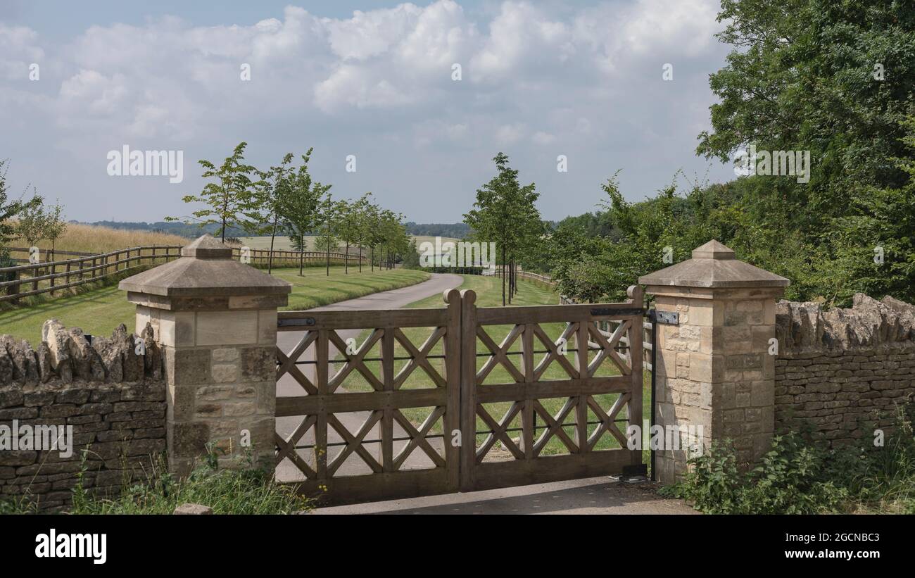 Looking down a driveway through ornate wooden gates Stock Photo - Alamy