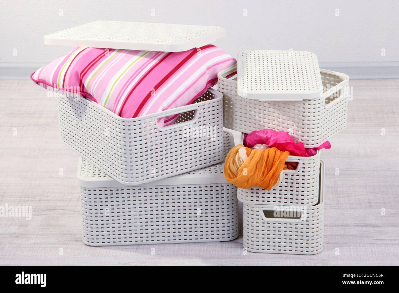 Plastic baskets with things in floor on room background Stock Photo - Alamy