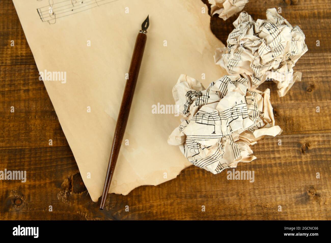 Crumpled paper balls with ink pen and music sheet on wooden background ...