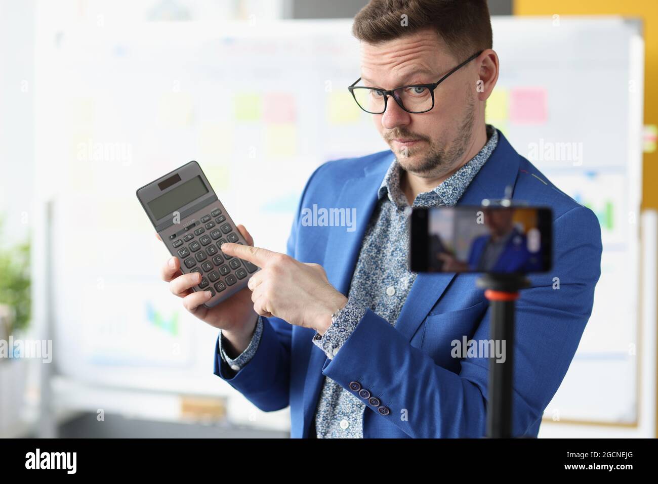 Male blogger calculates profitable interest bank rates on calculator ...