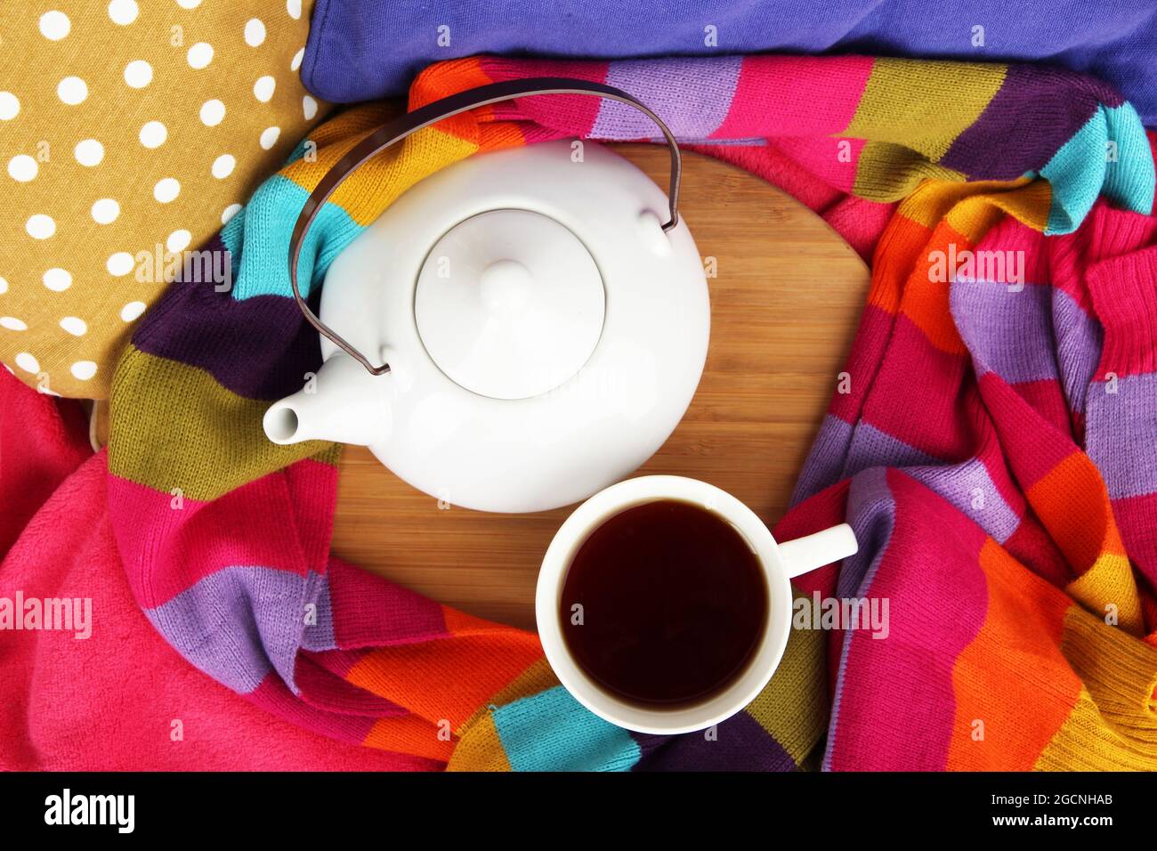 Cup and teapot on wooden stand and scarf on bed close up Stock Photo ...