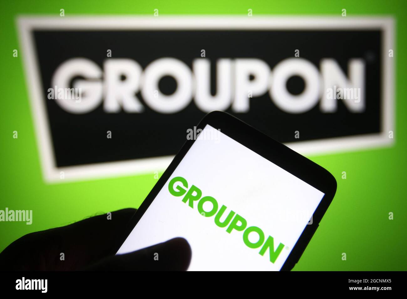 In this photo illustration a Groupon logo is seen on a smartphone and a ...