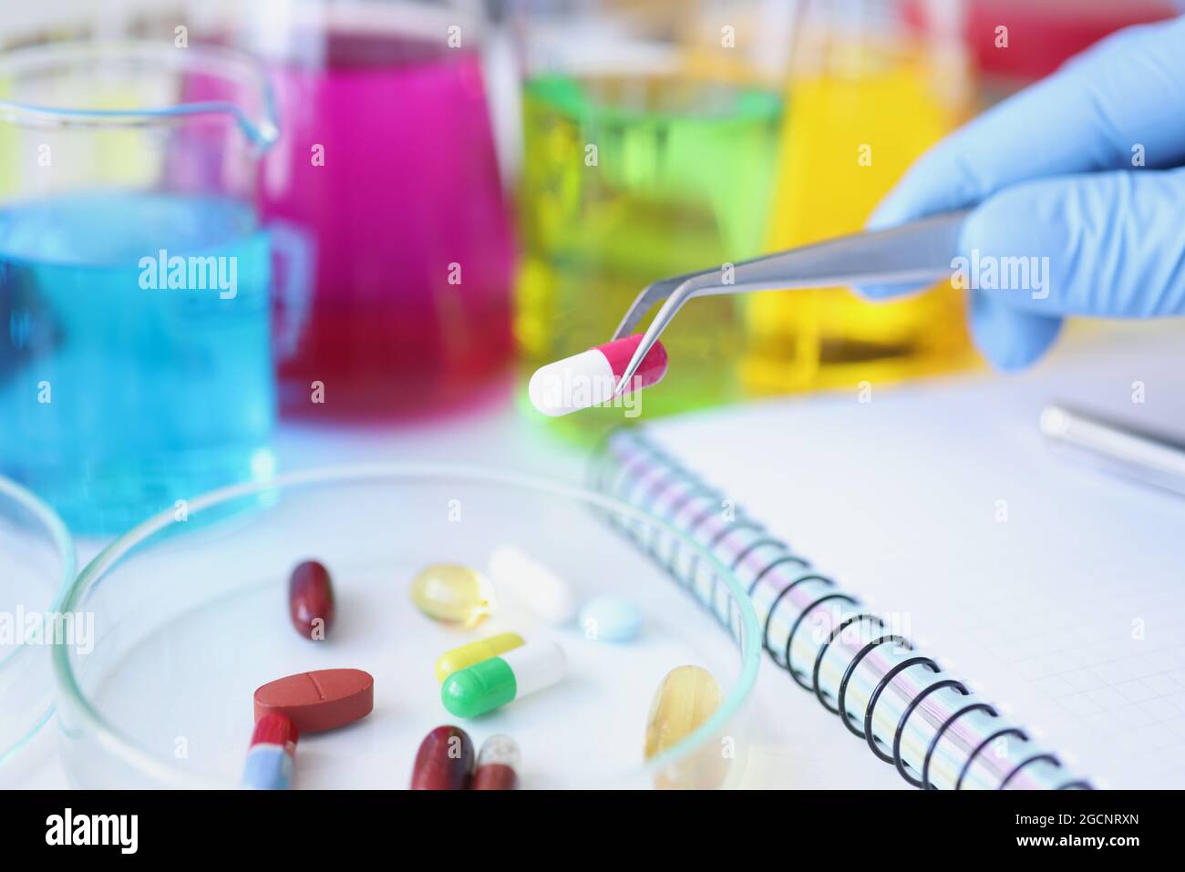 Scientist holds medical pill in forceps in laboratory closeup Stock ...