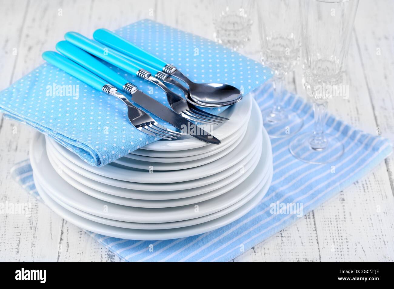Clean dishes on wooden table on light background Stock Photo - Alamy