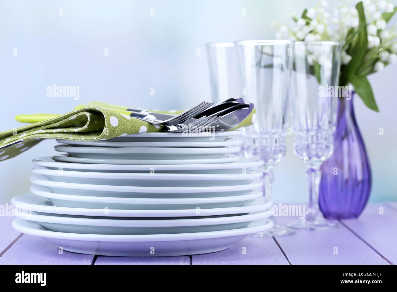 Clean dishes on wooden table on light background Stock Photo - Alamy