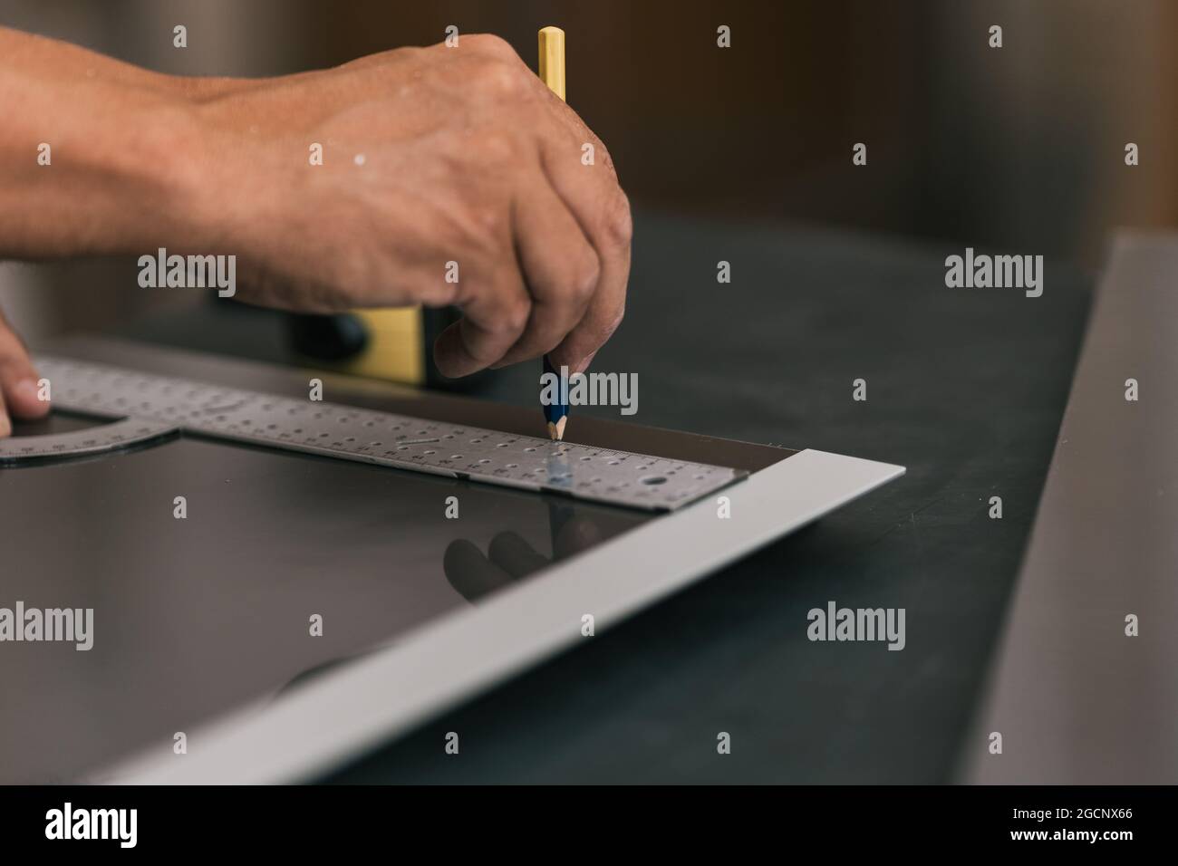Man drawing a line using a square on a surface in a workshop Stock ...