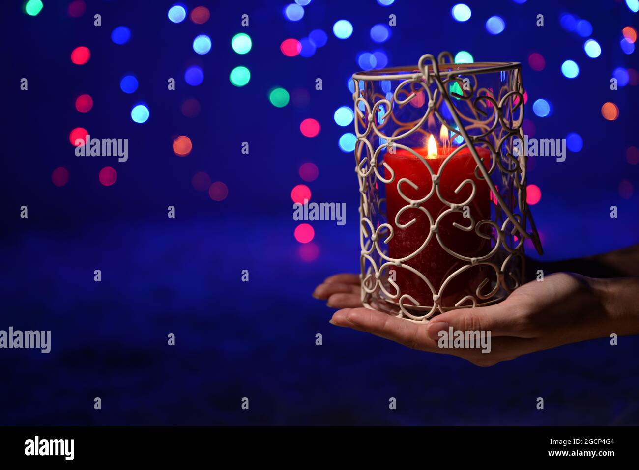 Candle in hand on blur lights background Stock Photo - Alamy