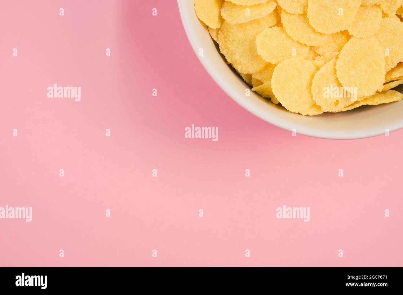 Bowl of cornflakes isolated on a pink background with free space for ...