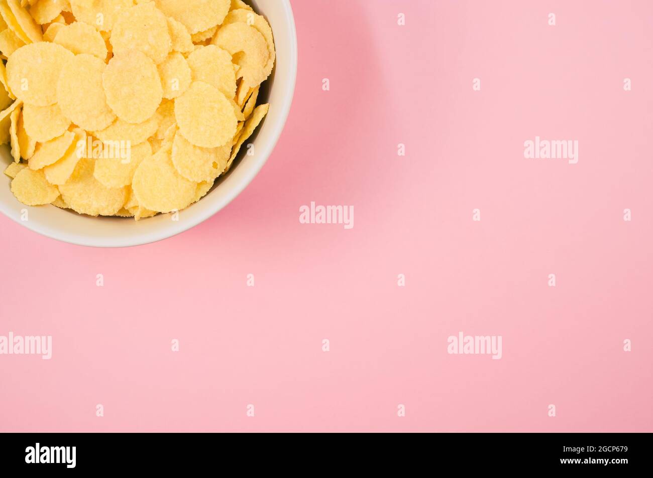 Bowl of cornflakes isolated on a pink background with free space for ...