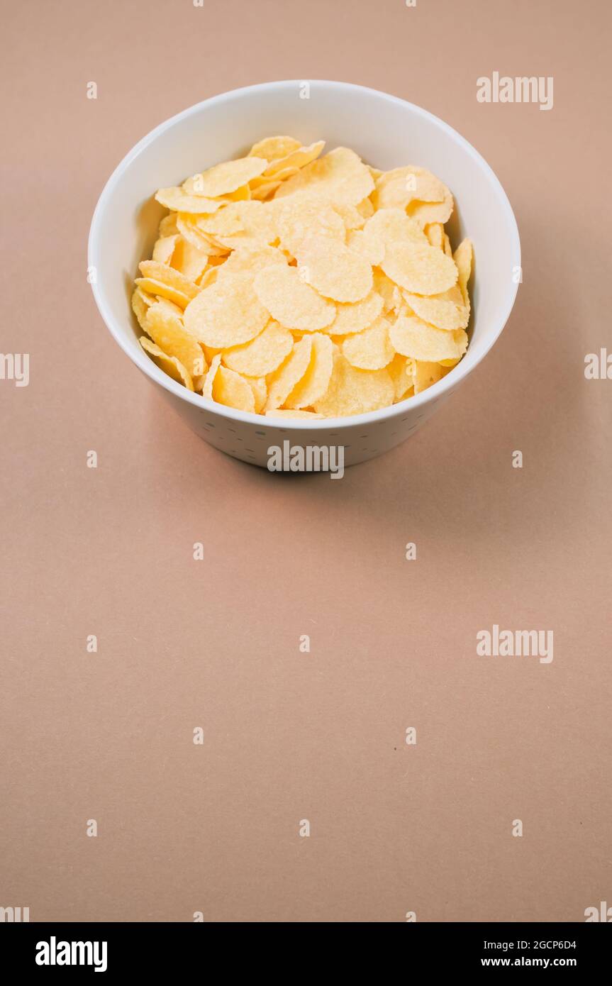 Bowl of cornflakes isolated on a brown background with free space for ...
