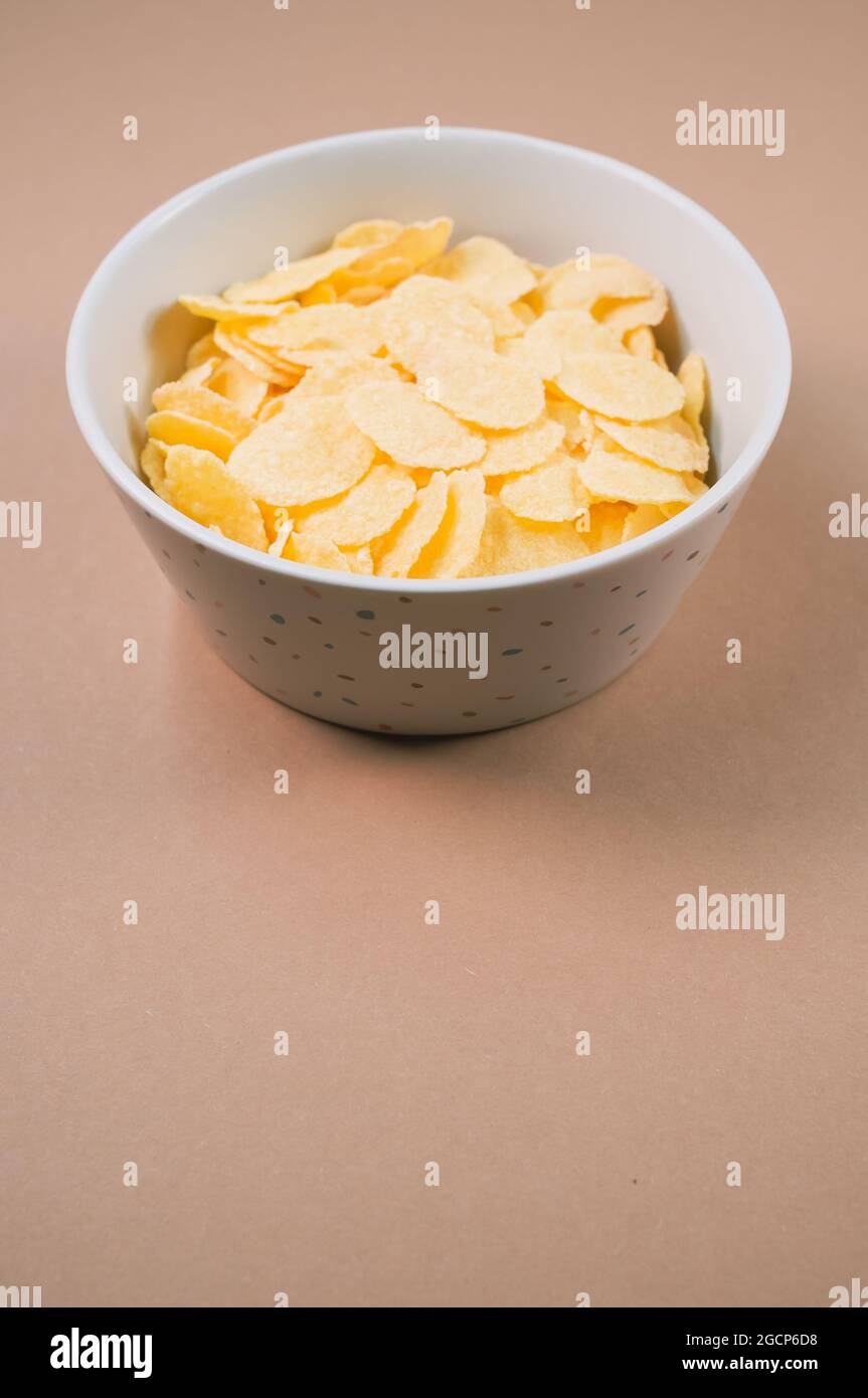 Bowl of cornflakes isolated on a brown background with free space for ...