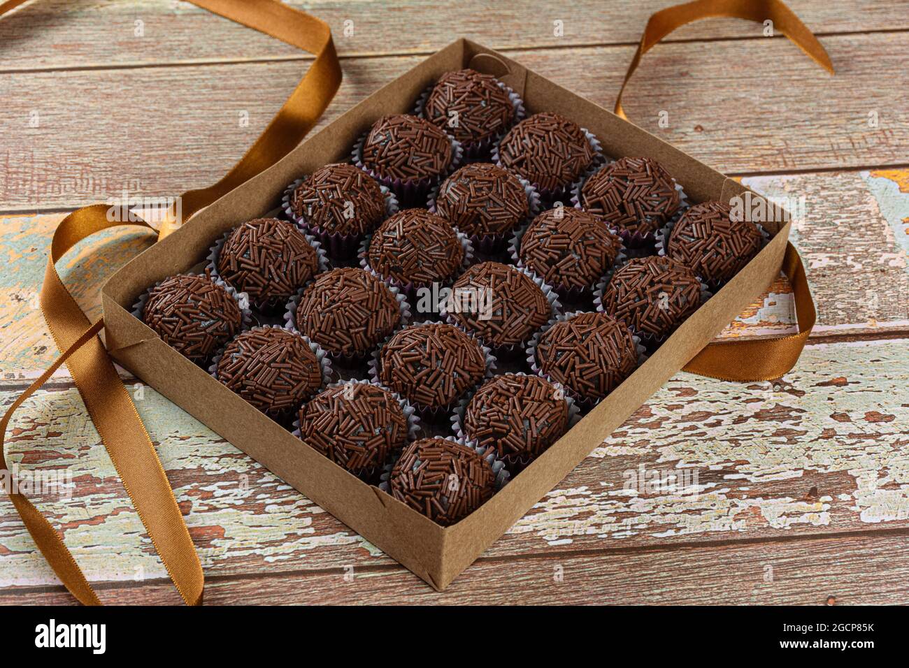 Box with several brigadeiros lined up next to a bow ribbon. Brazilian ...