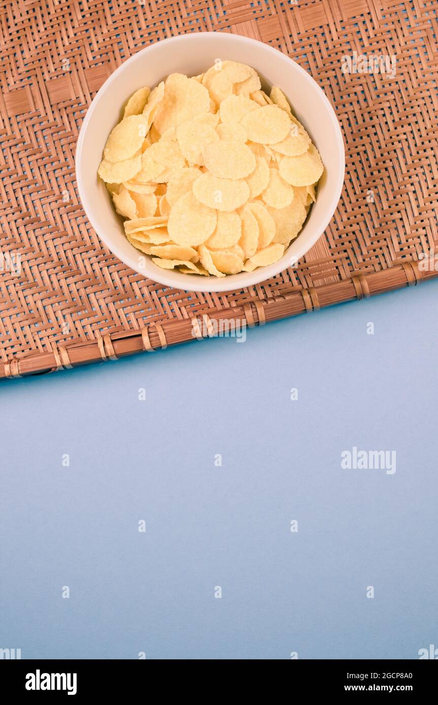 Bowl of cornflakes on a wooden placemat isolated on white surface with ...