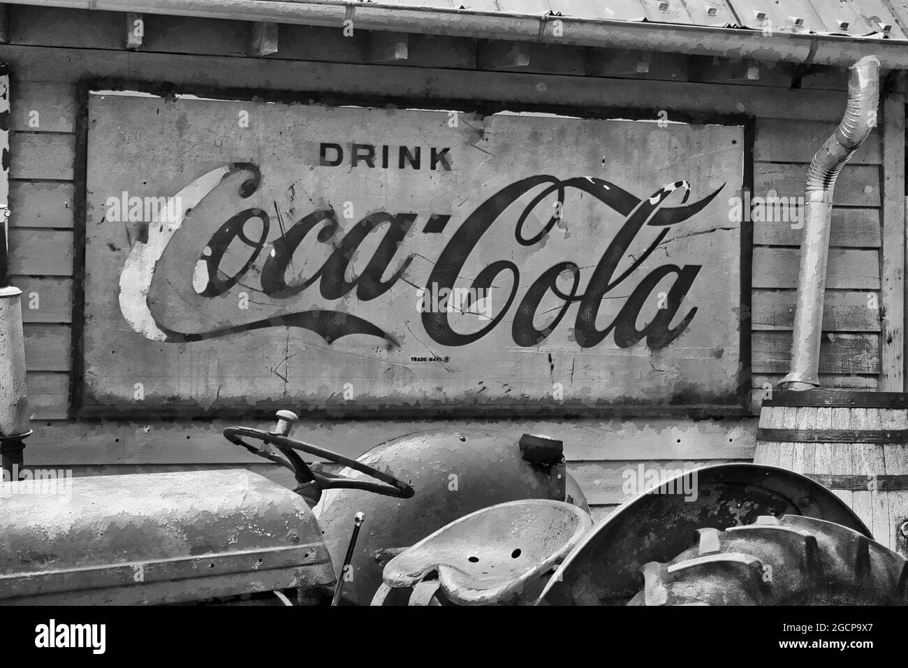 A vinatge tractor parked under a rusted sign for Coca Cola at the Mast ...