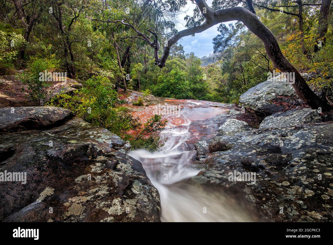 a large waterfall next to a rock in patonga Stock Photo - Alamy