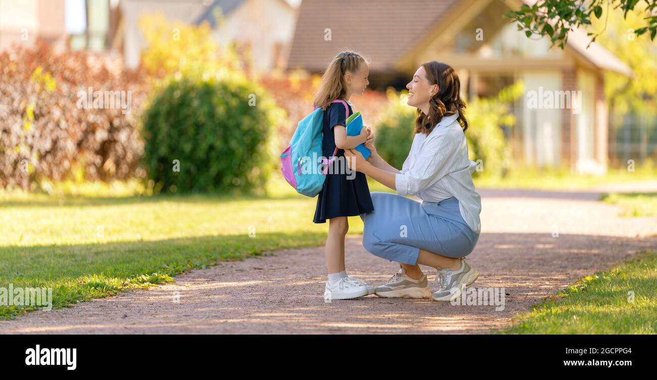 Parent and pupil of primary school going hand in hand. Woman and girl ...